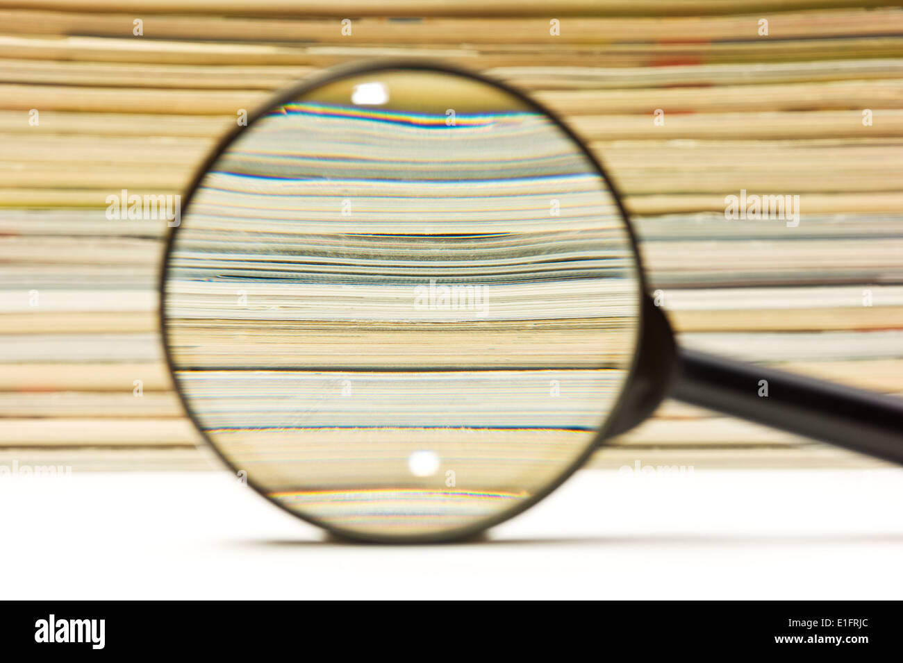 magnifier on the background of the stack of magazines Stock Photo - Alamy