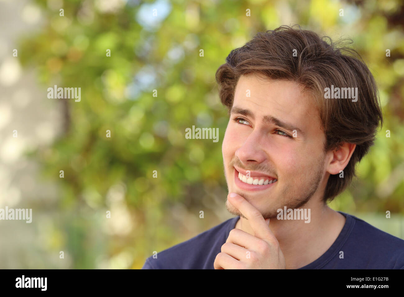 Happy man thinking outdoor with a green background Stock Photo - Alamy