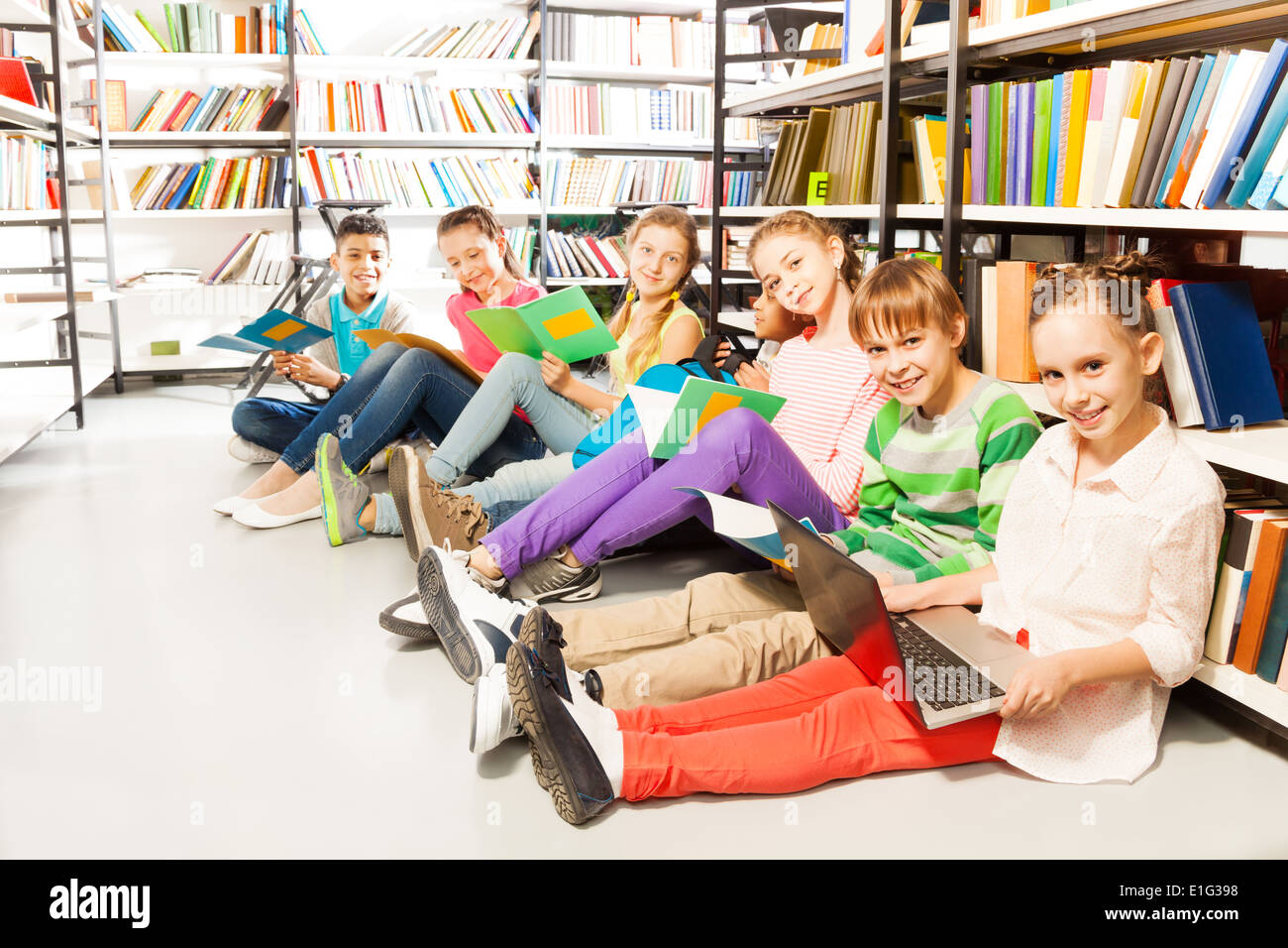 Six smiling children sitting in a row on floor Stock Photo - Alamy
