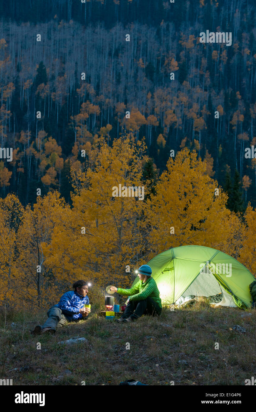 A man and a woman camping at night near yellow aspens, Durango ...