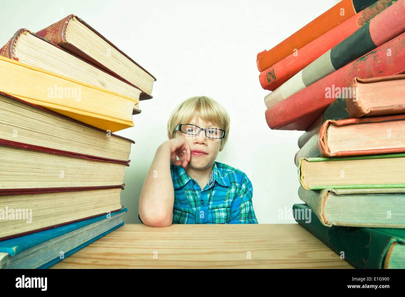 Bored child with a pile of books to learn Stock Photo - Alamy