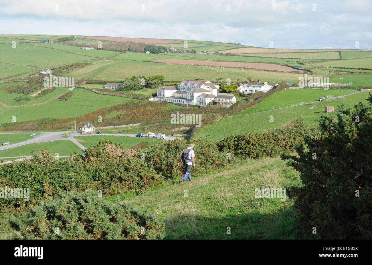 A hiker walks the South West Coastal Path across Baggy Point in North ...