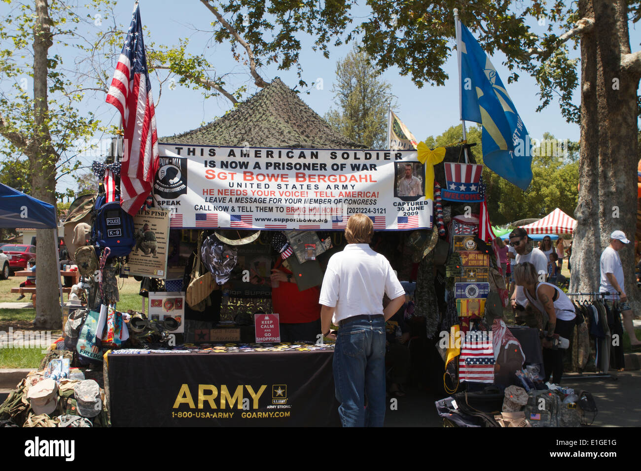 A patriotic military stall at a street fair with a sign asking for ...