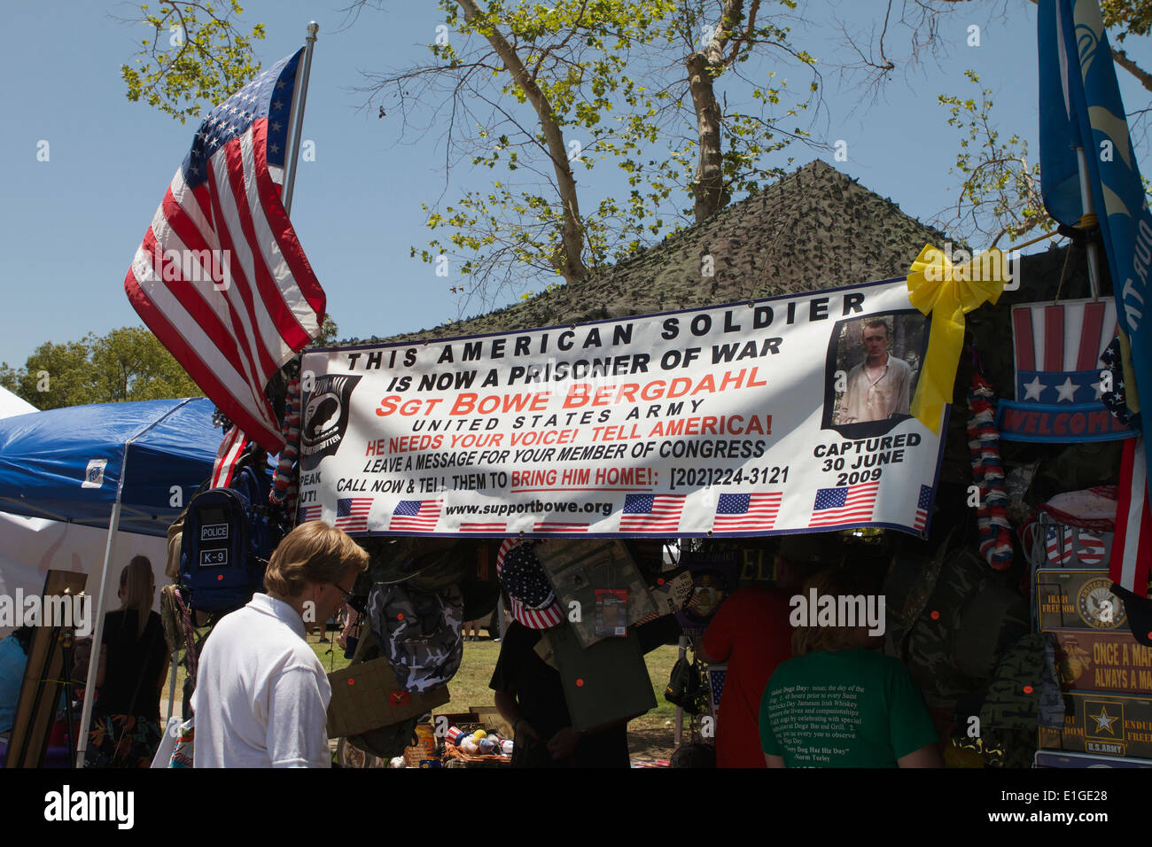 A patriotic military stall at a street fair with a sign asking for ...