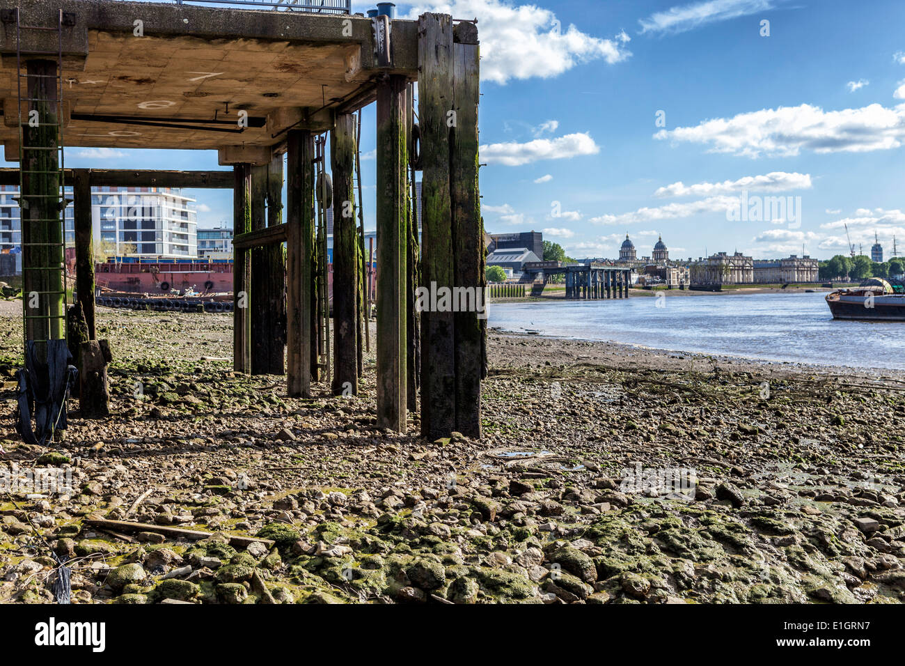 Thames river bed at low tide at Greenwich with old piers, new apartment ...