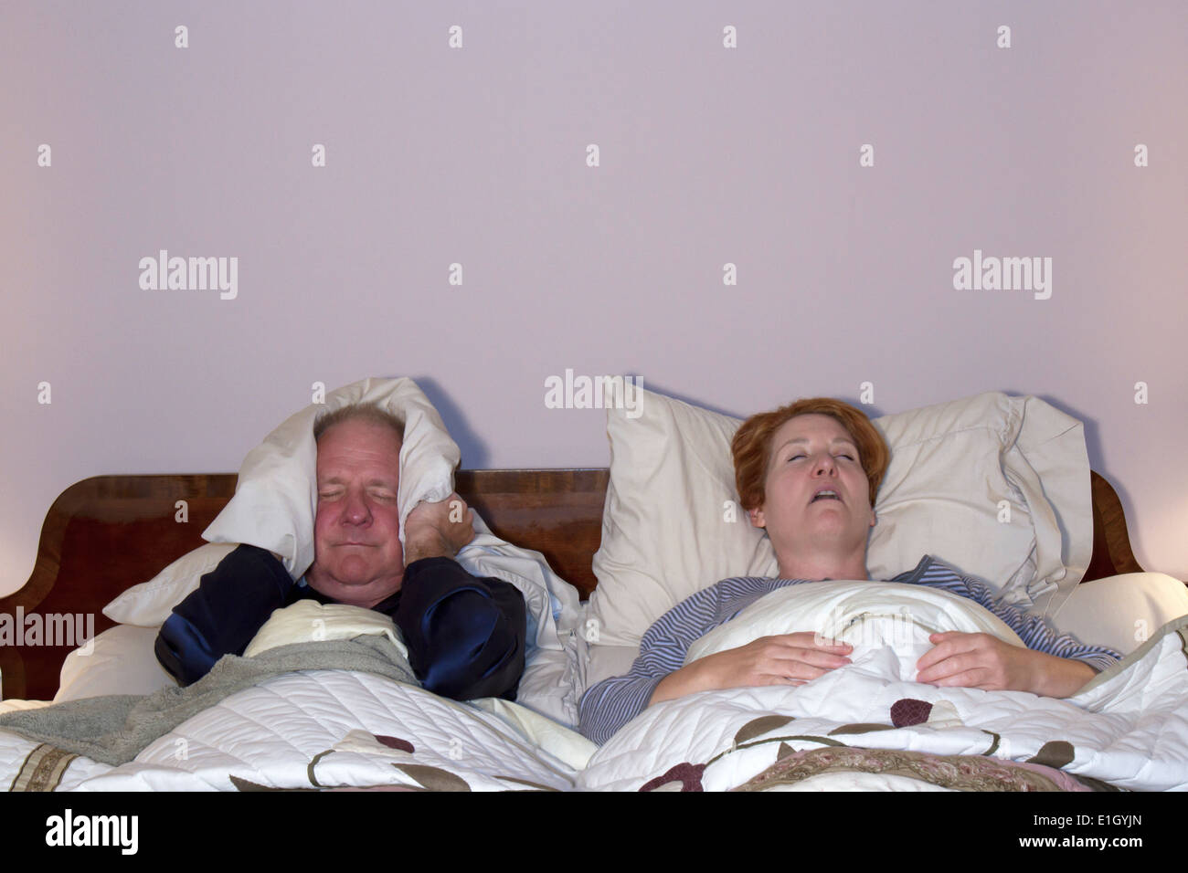 Mature couple in bed with wife snoring and husband covering ears Stock ...