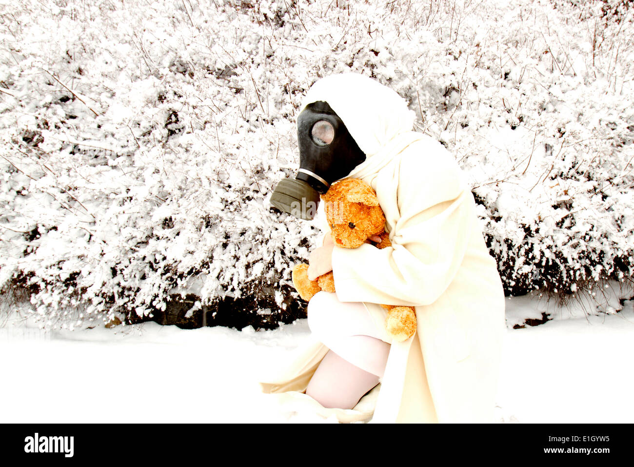 Woman dressed in white wearing a gas mask and hugging a teddy bear ...