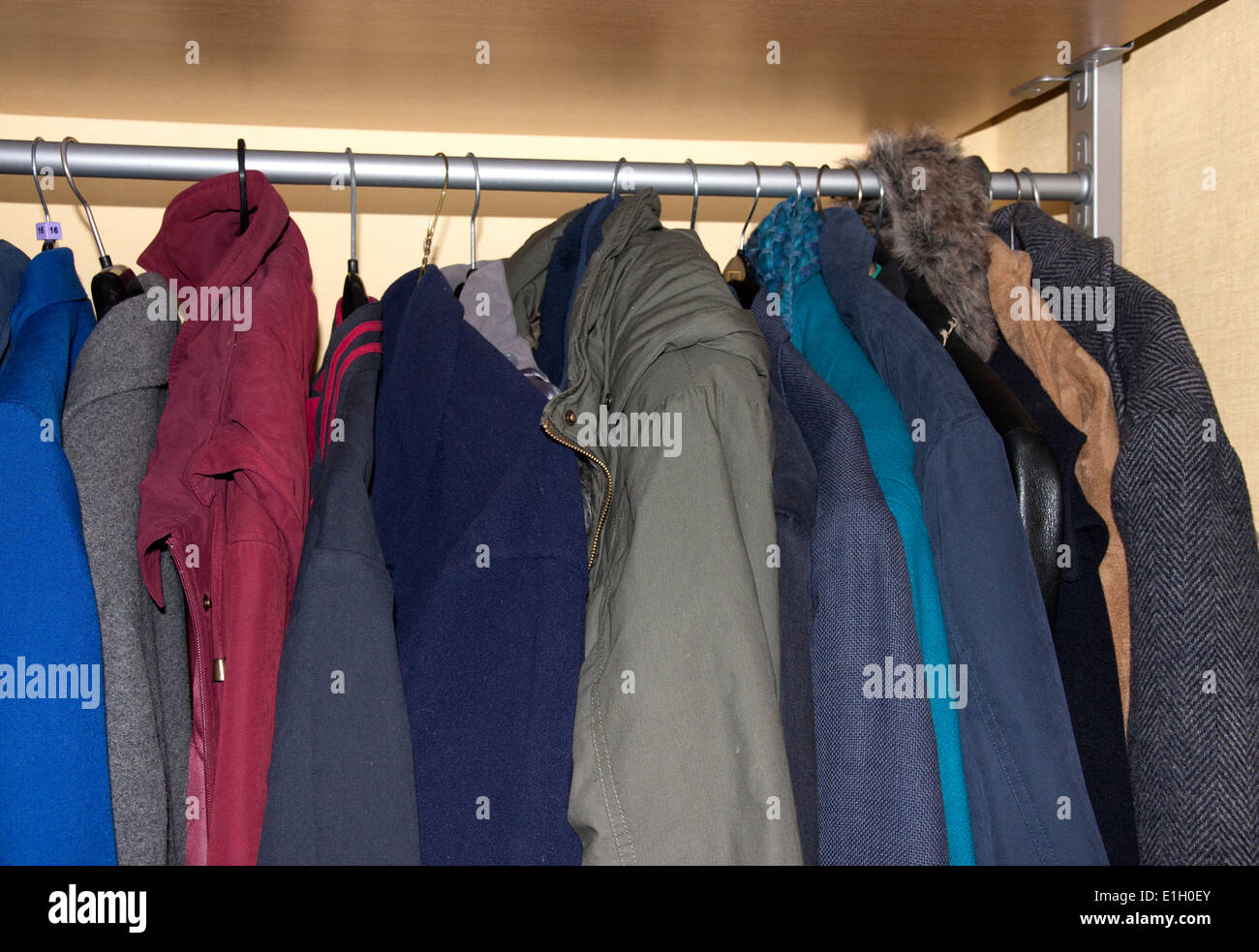 Coats hanging from a rail in a wardrobe Stock Photo - Alamy