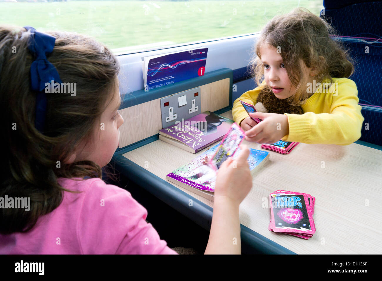 Children playing top trumps card game during a train journey. United ...