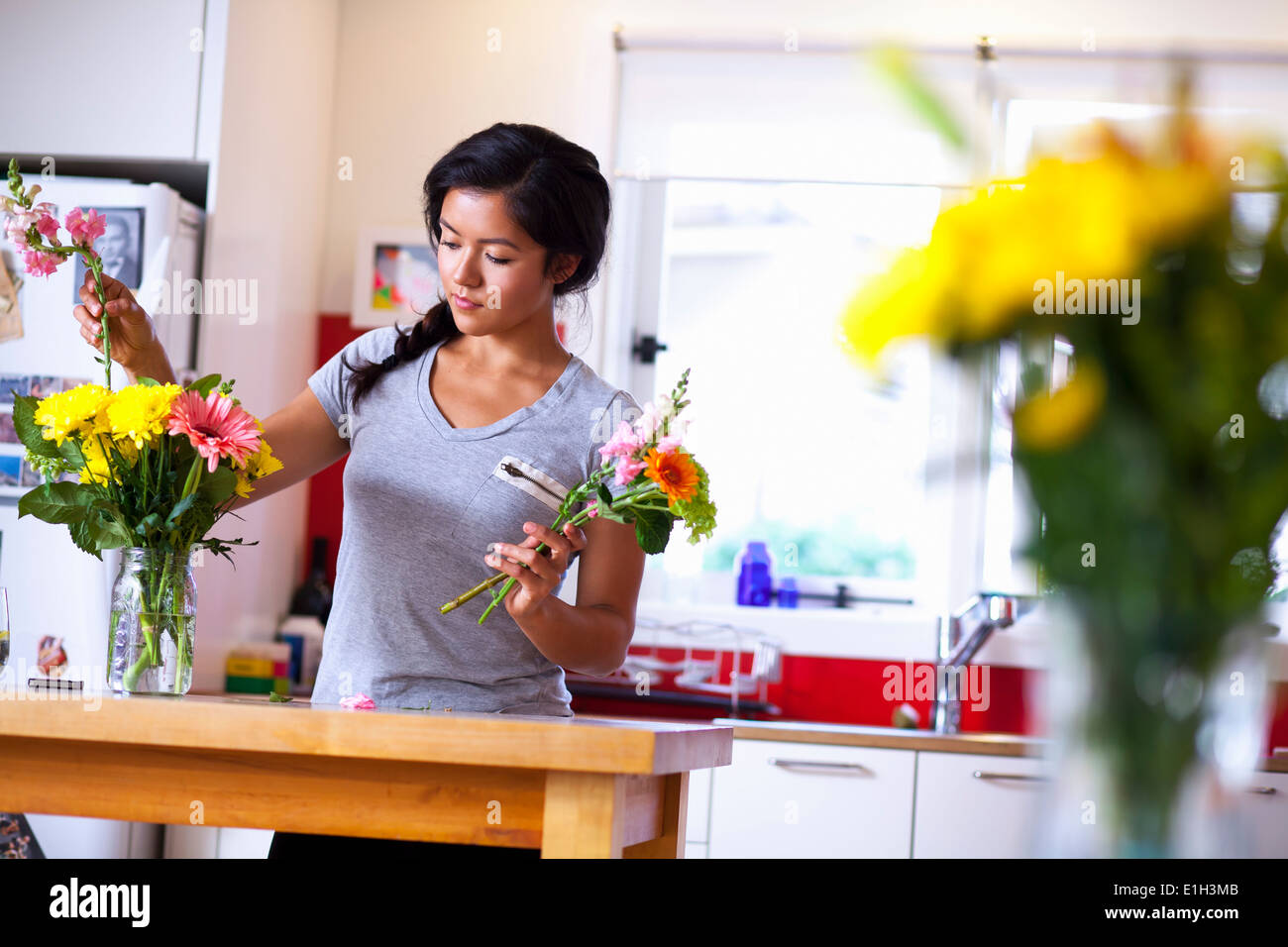 Young woman arranging flowers in kitchen Stock Photo - Alamy