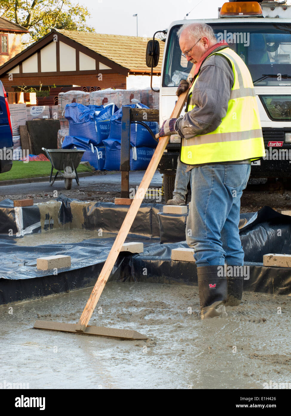 self building house, pouring floor slab, man roughly levelling concrete ...