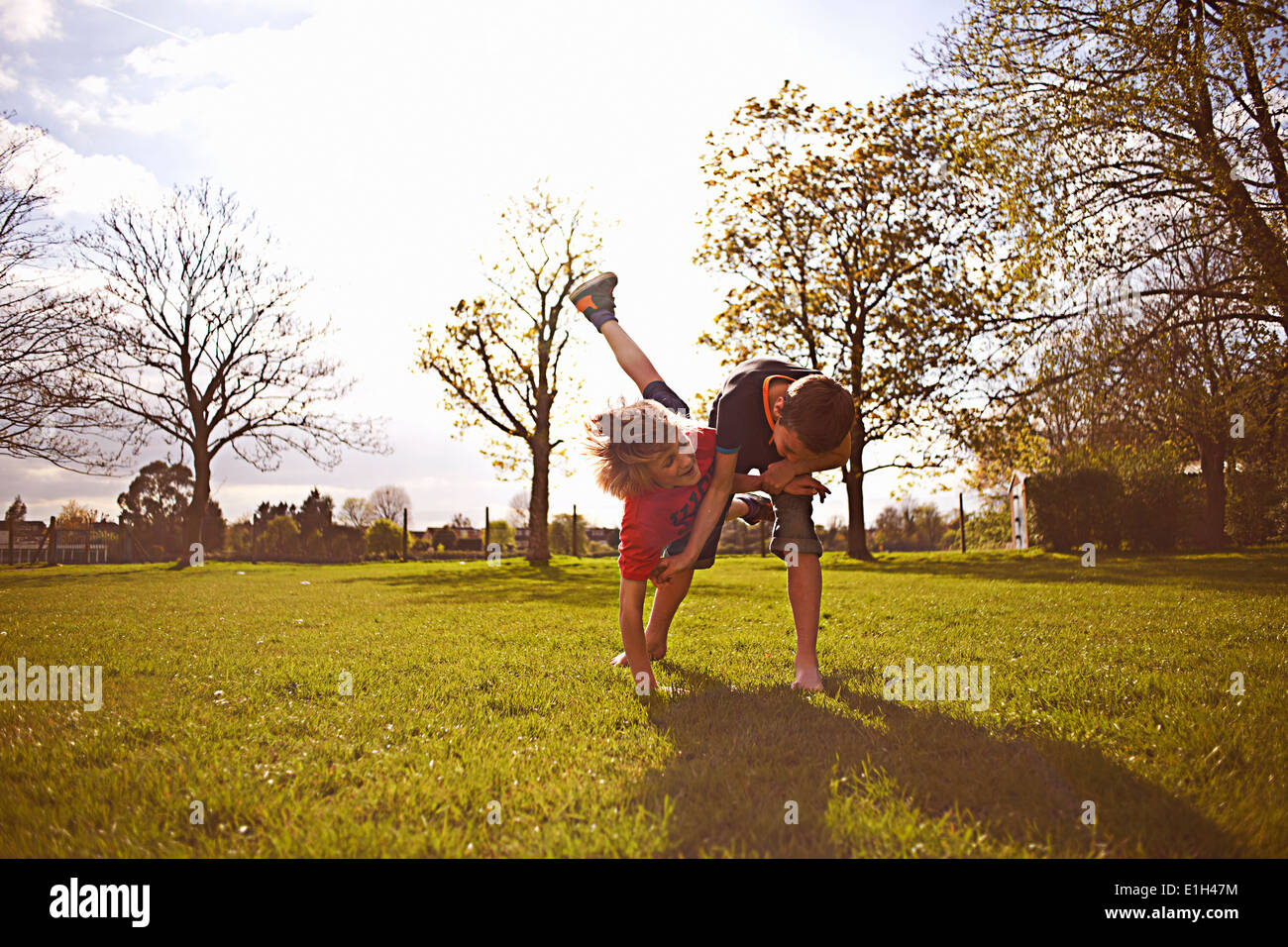 Boys play fighting on playing field Stock Photo - Alamy