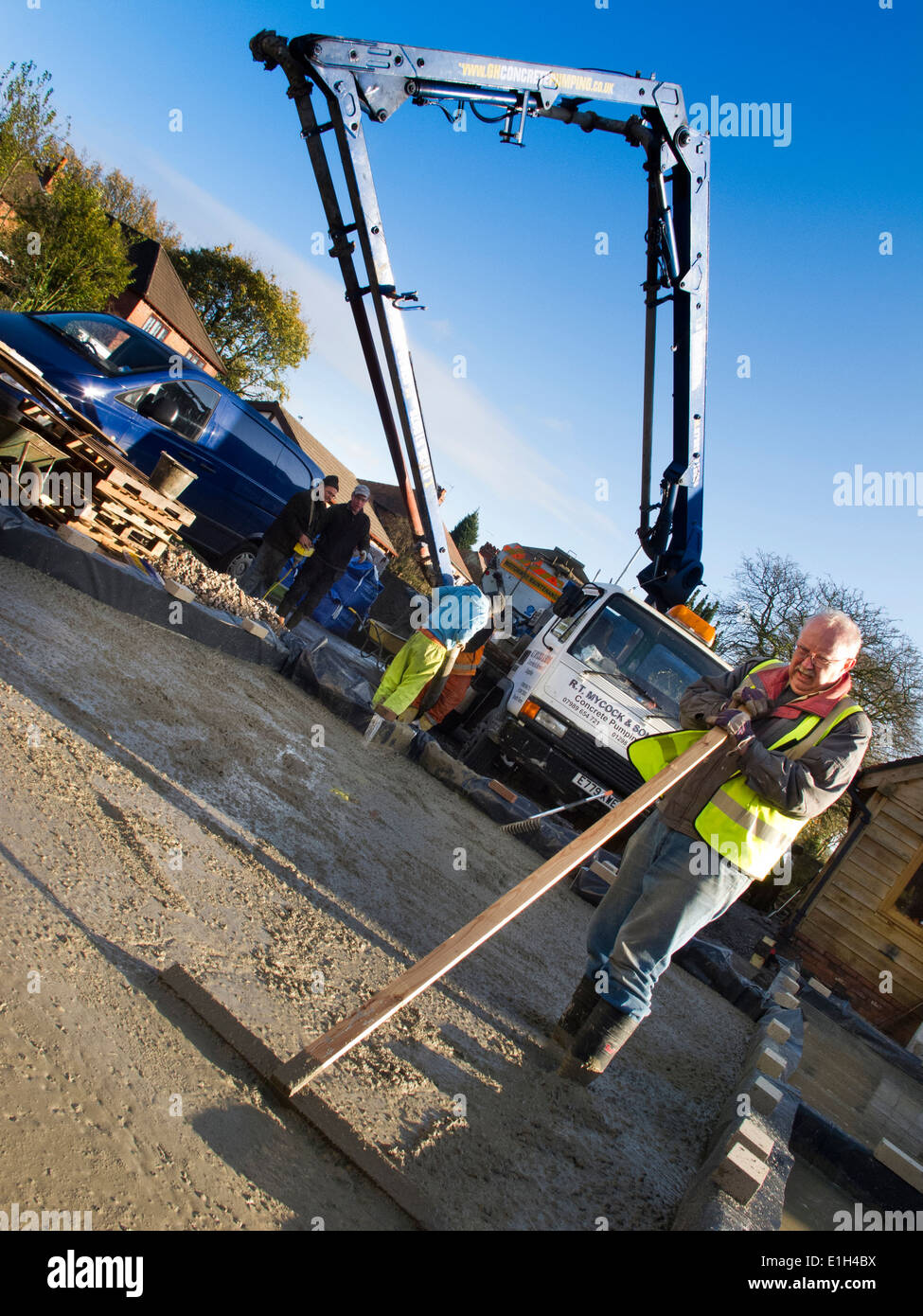 self building house, man tamping freshly poured concrete floor slab ...