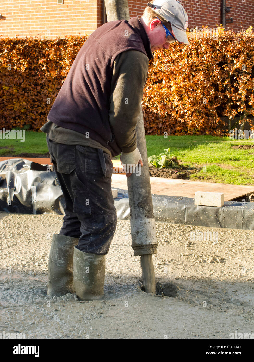 self building house, man pouring floor slab, directing concrete pump ...