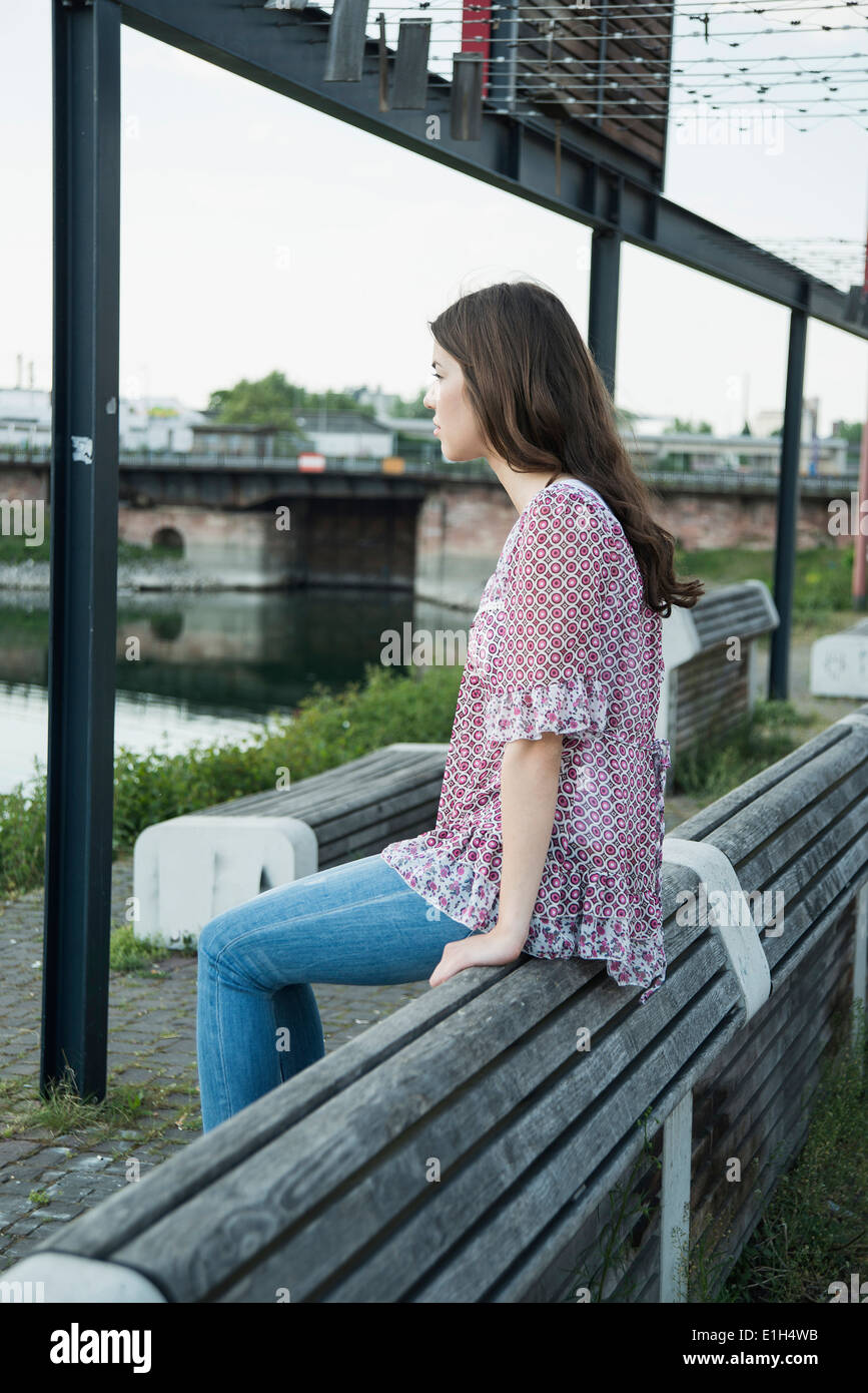 Young woman sitting on bench Stock Photo - Alamy