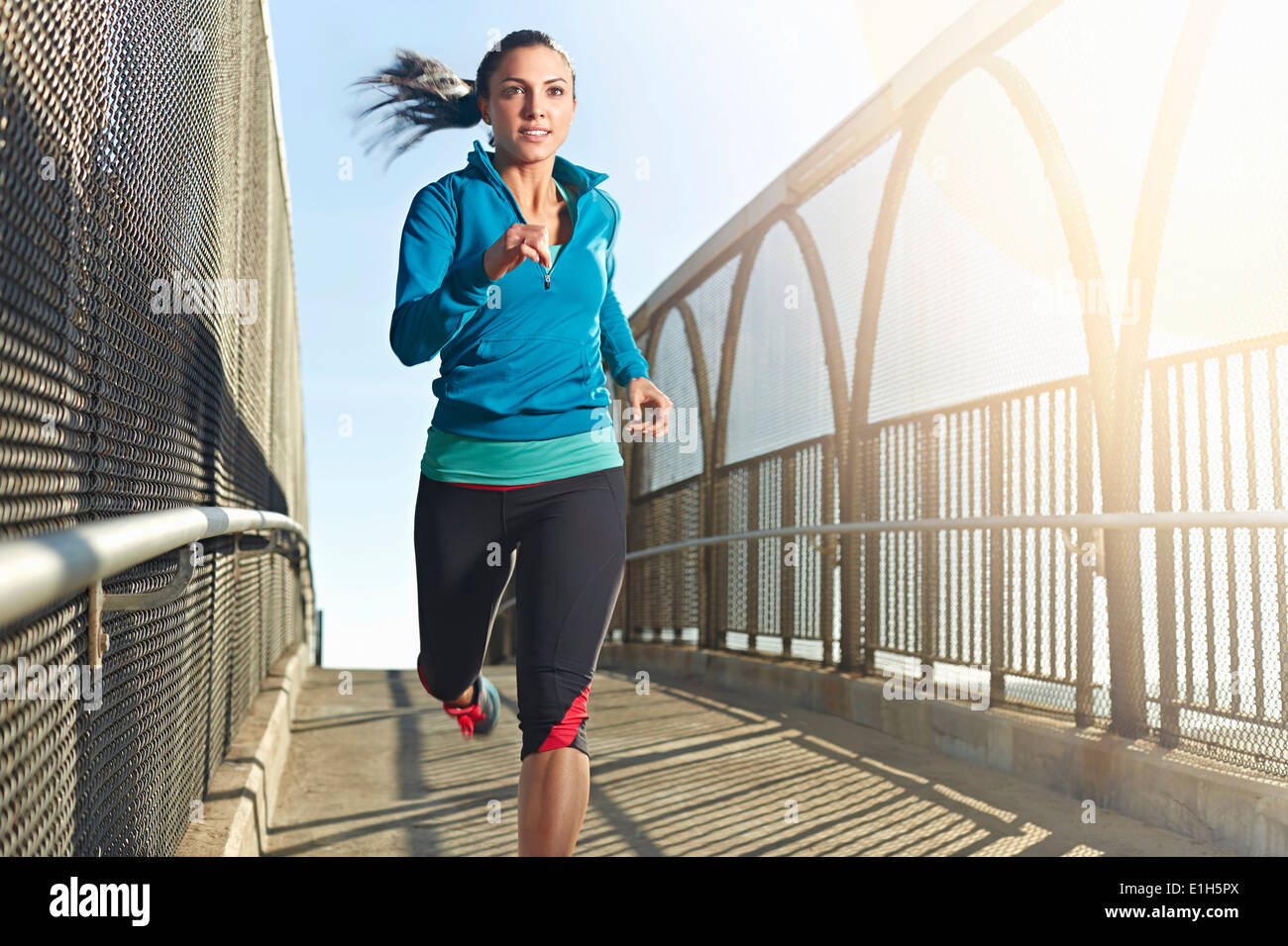 Woman running over bridge Stock Photo - Alamy