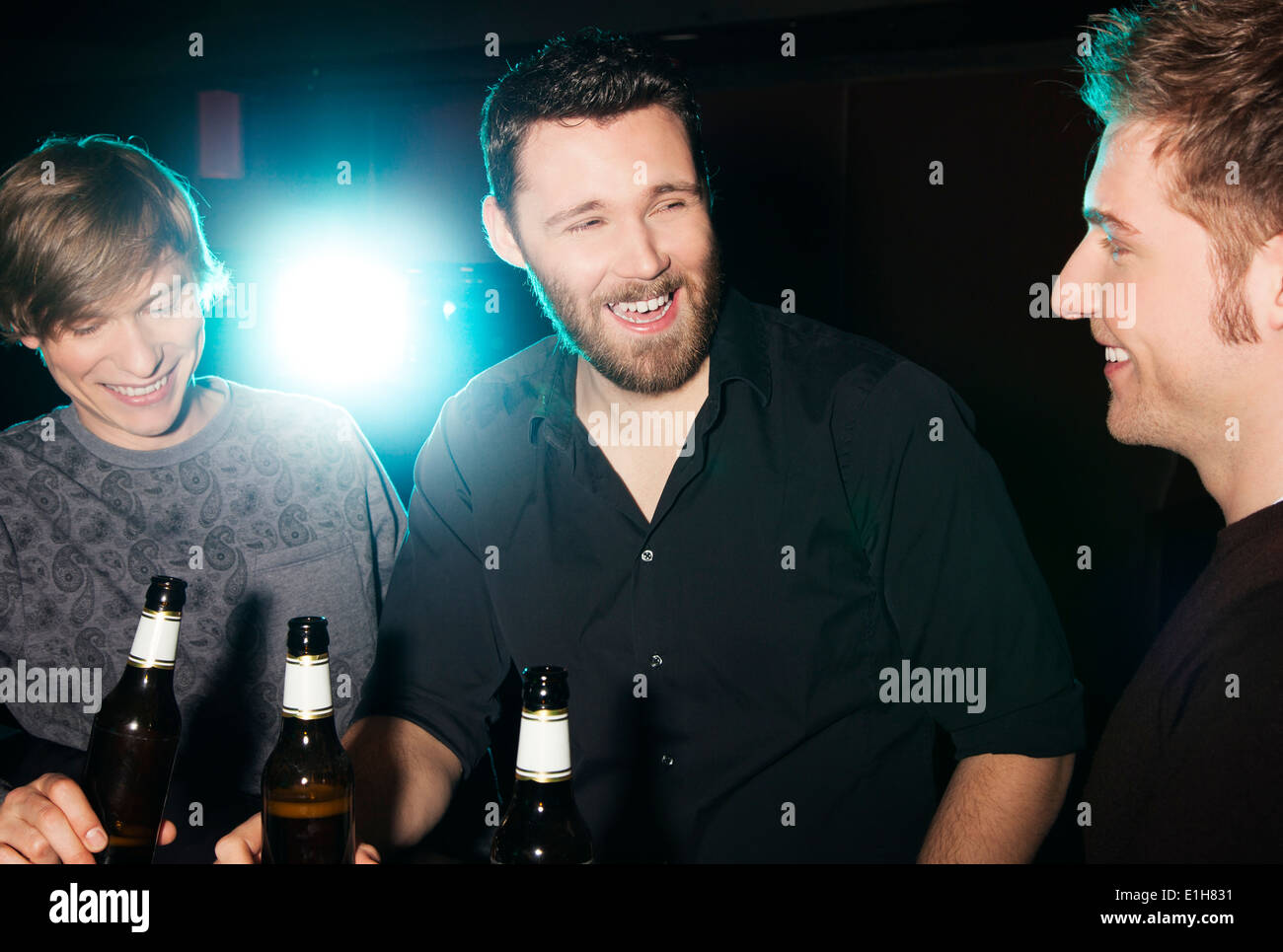Three male friends drinking bottled beer in nightclub Stock Photo - Alamy