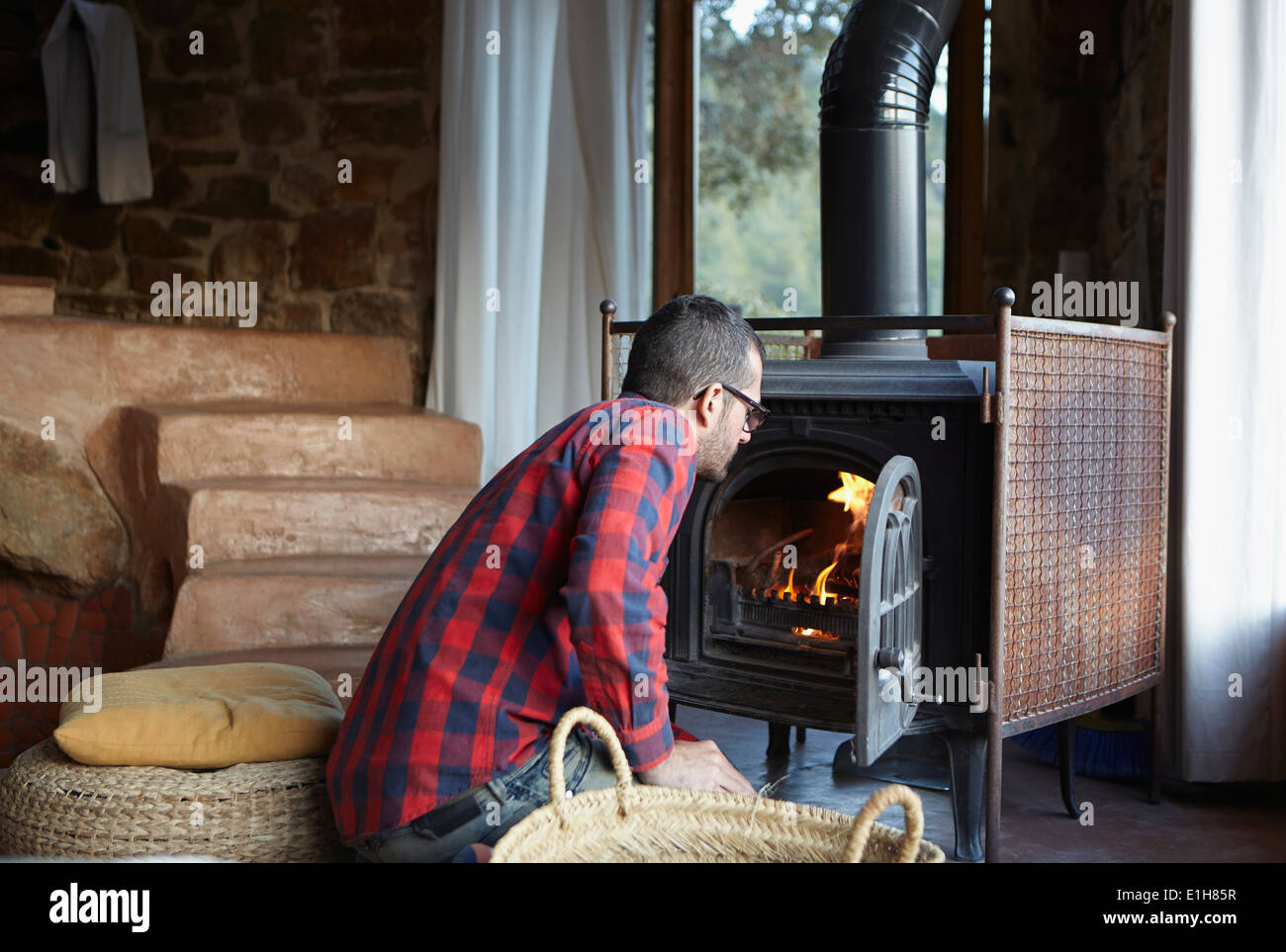 Mid adult man watching log burning fire Stock Photo - Alamy
