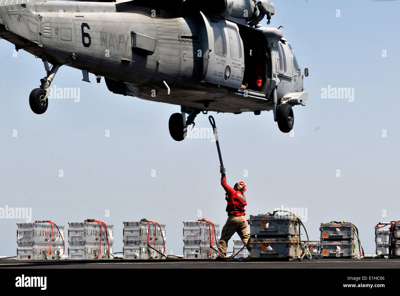 U.S. Navy Lt. Brian Helman hands a cargo hook to a crewman aboard an MH ...
