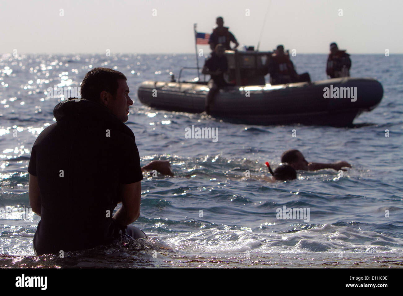 A safety swimmer aboard USS New Orleans sits on the ship's stern gate ...
