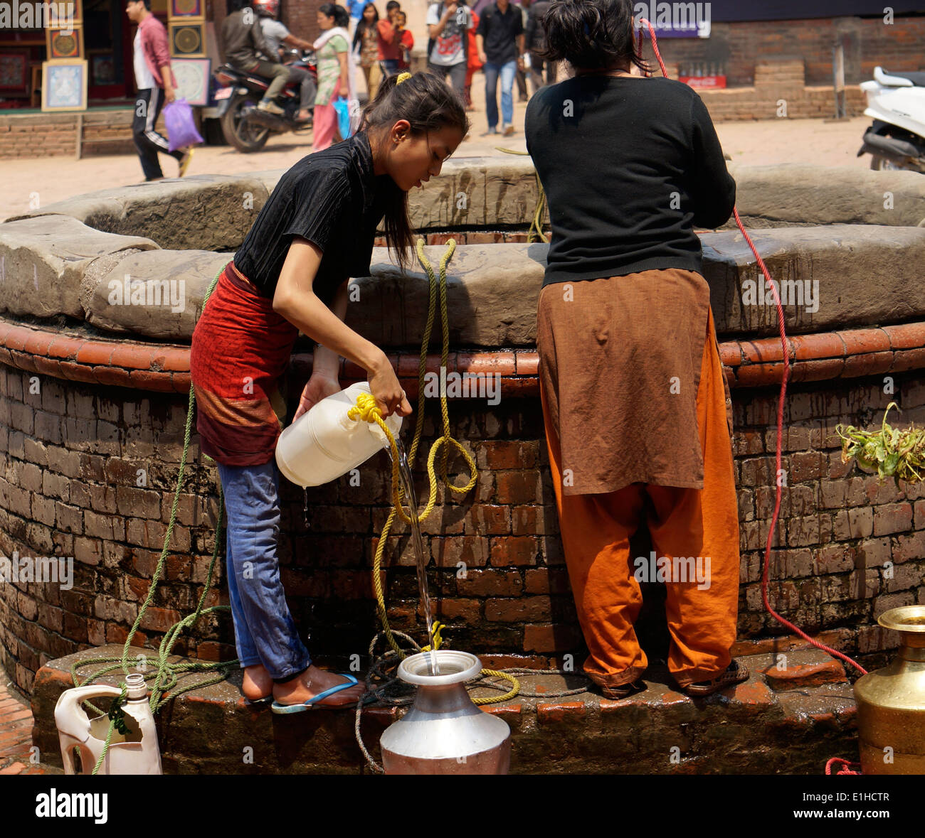 Two women at the well gathering water for daily use Stock Photo - Alamy