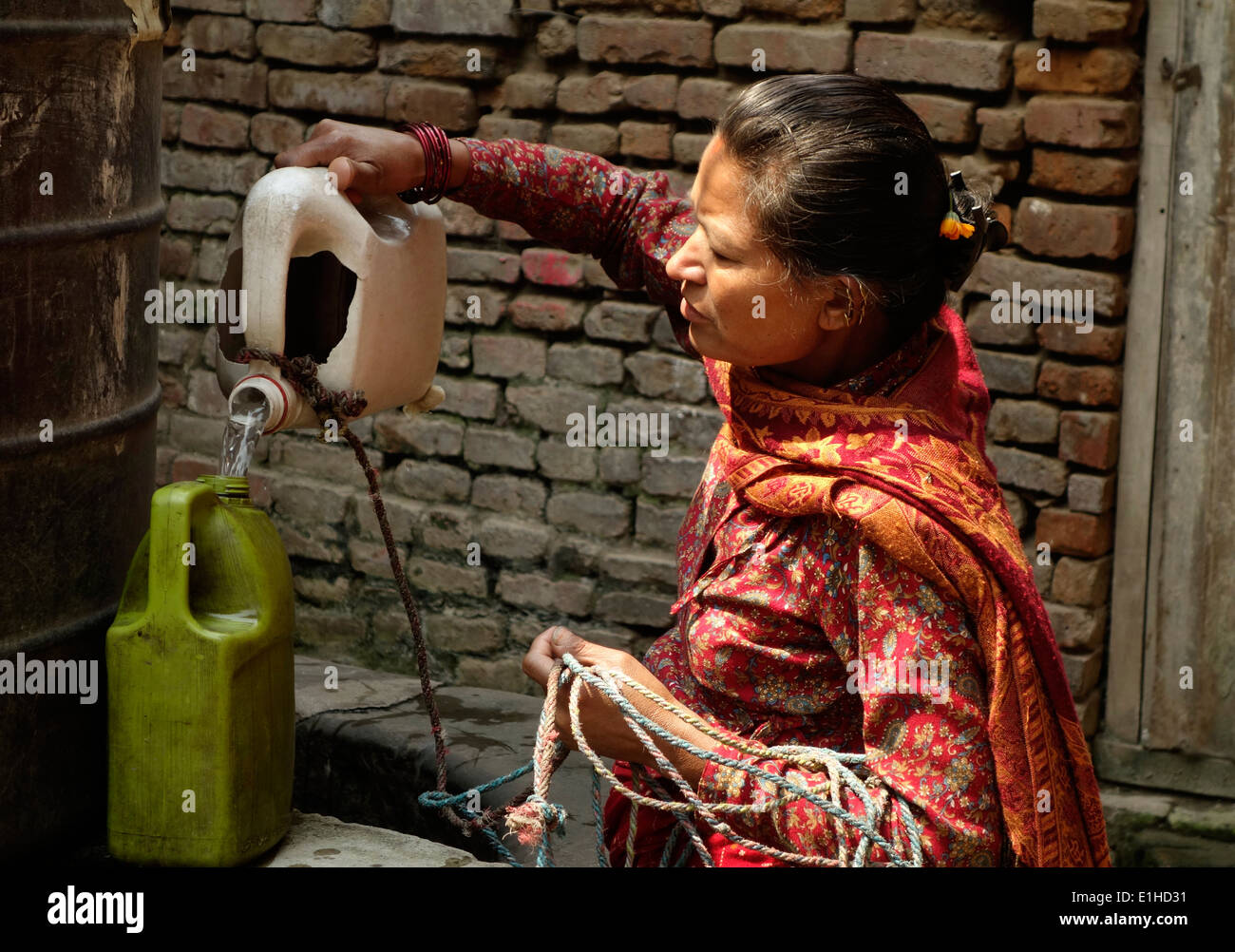 Woman is collecting water at well in Kathmandu Stock Photo - Alamy