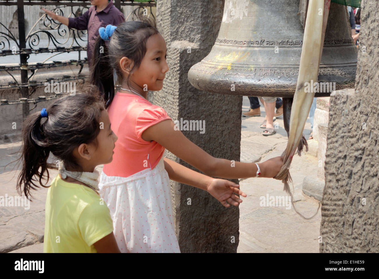 two young girls are ringing big bell at Swayambhunath temple,innocence ...
