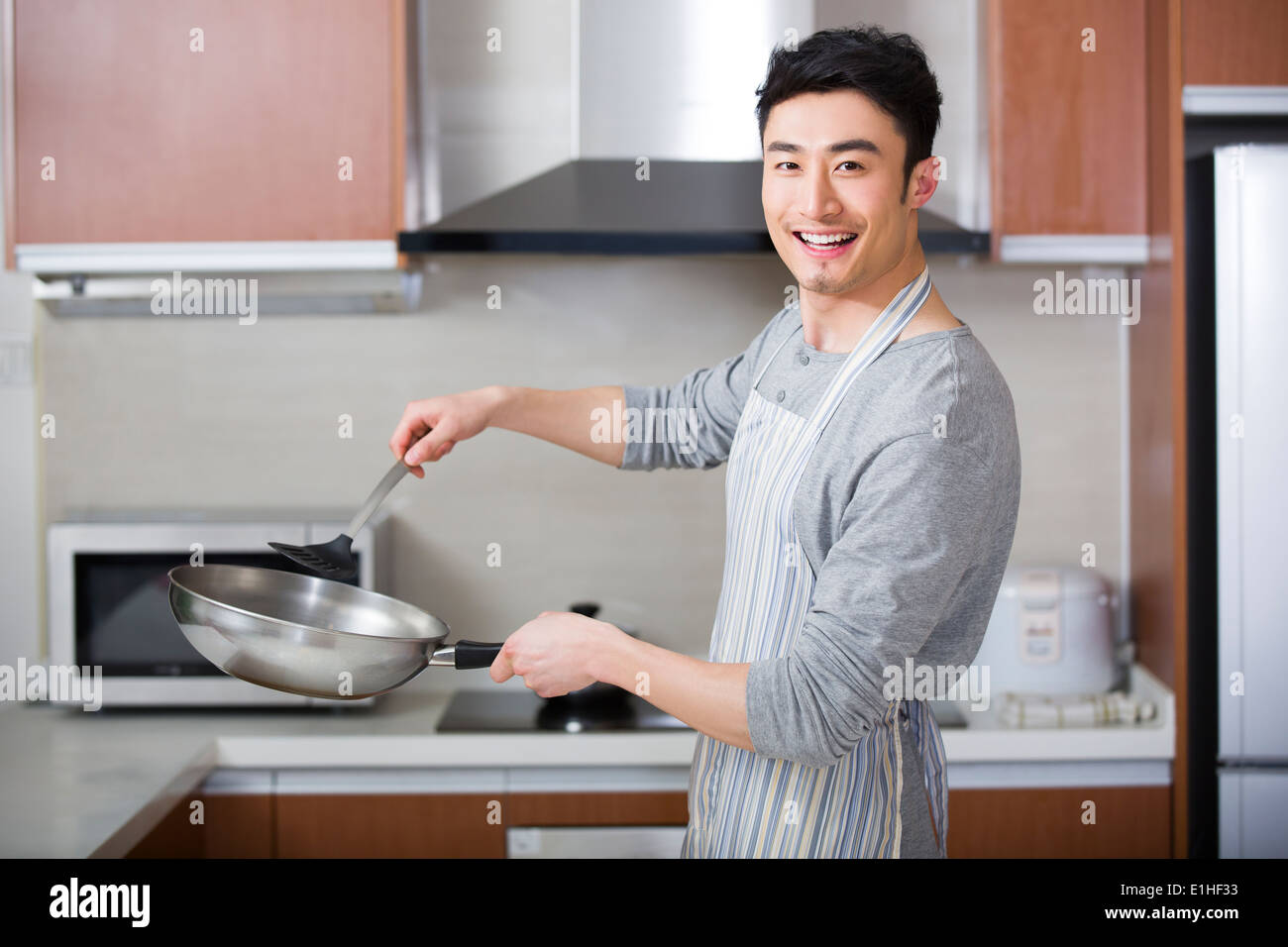 Cheerful young man cooking in kitchen Stock Photo - Alamy