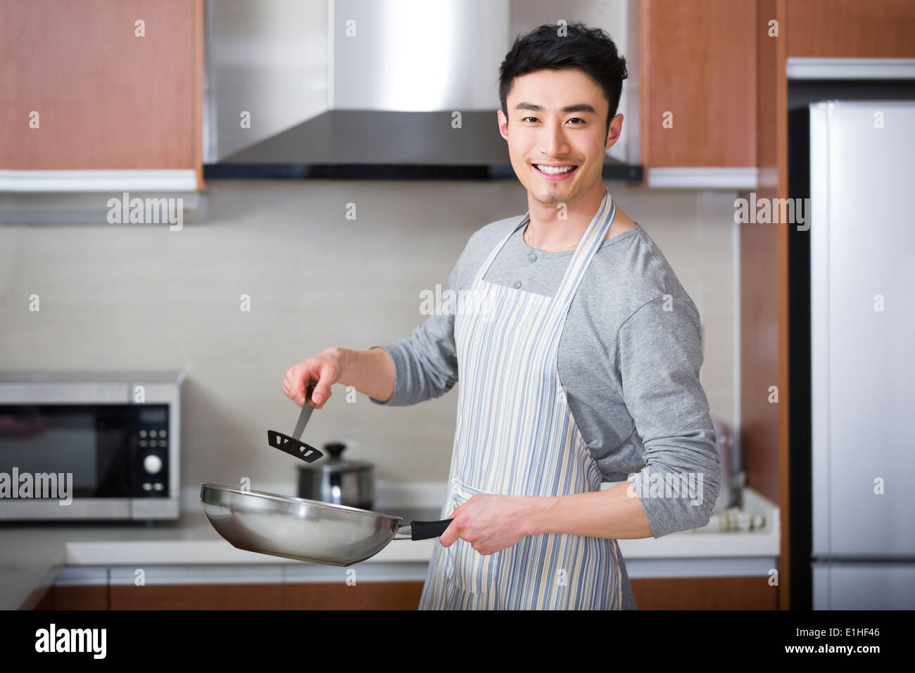 Cheerful young man cooking in kitchen Stock Photo - Alamy
