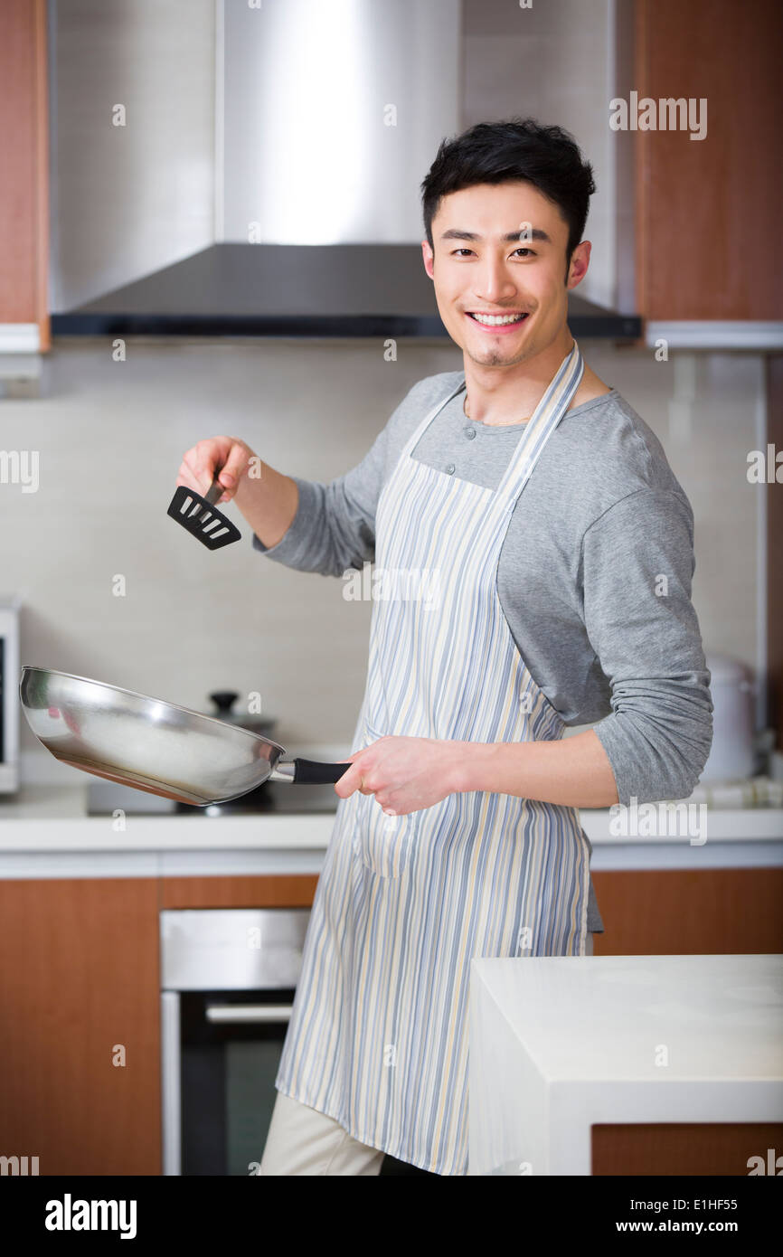 Happy young man cooking in kitchen Stock Photo - Alamy