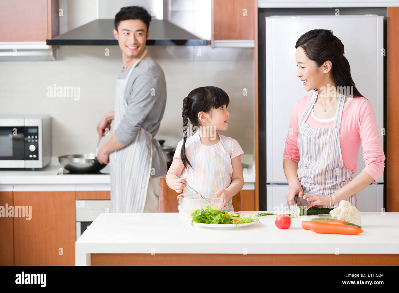 Happy young family cooking in kitchen Stock Photo - Alamy