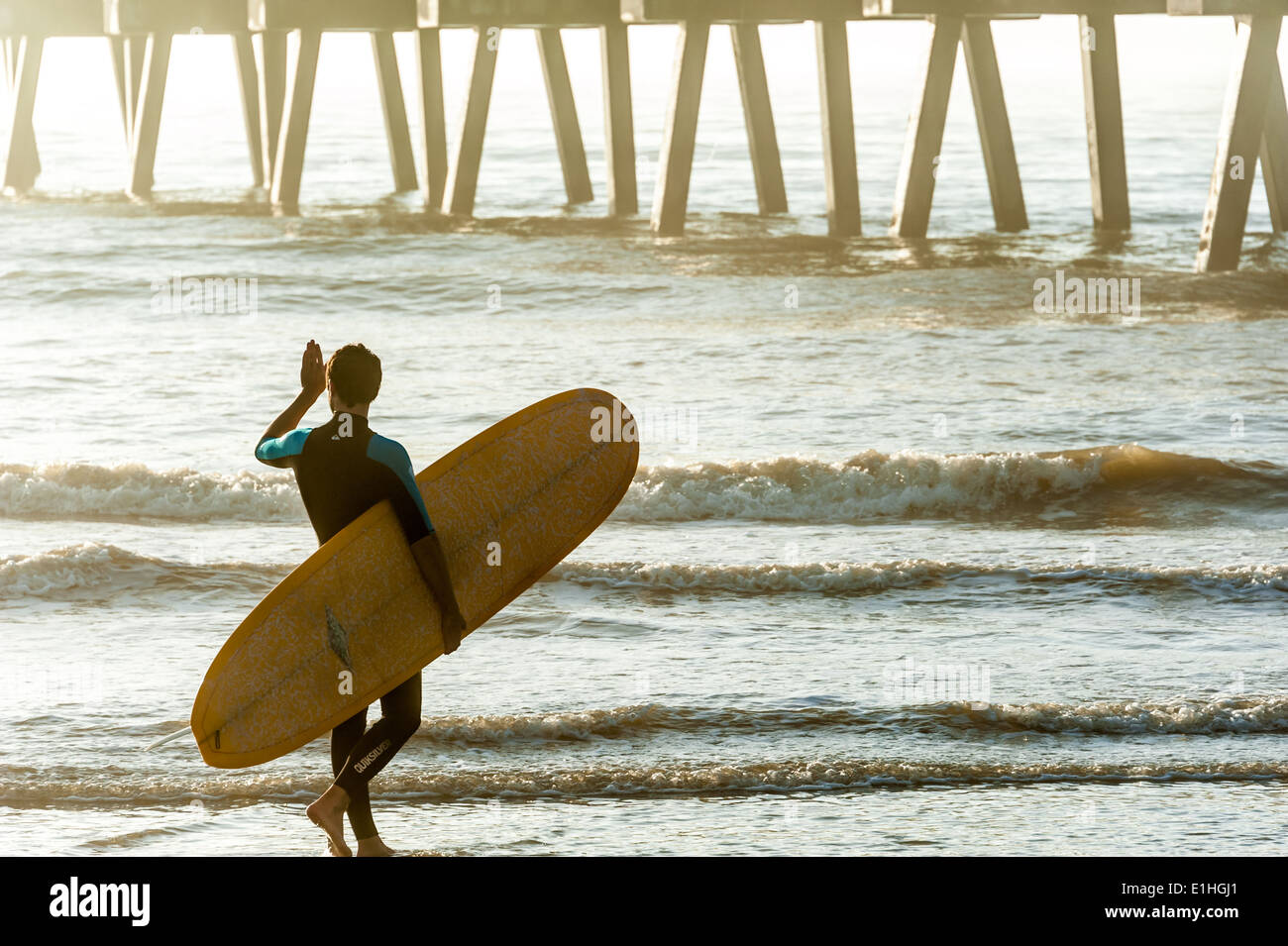 A Florida surfer shields his eyes from the glare of the rising sun as ...