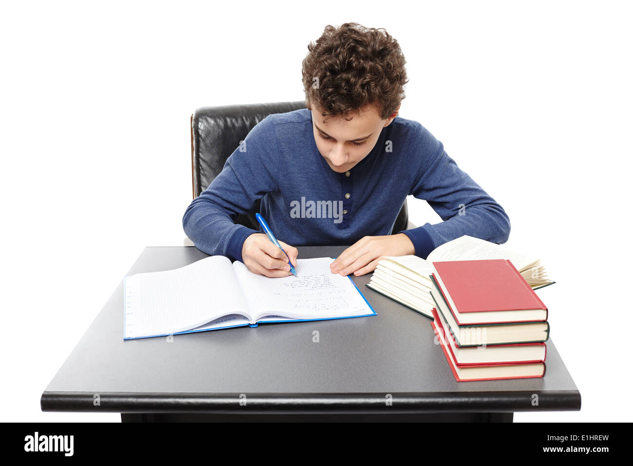 Studio shot of student sitting at his desk focused and doing his ...