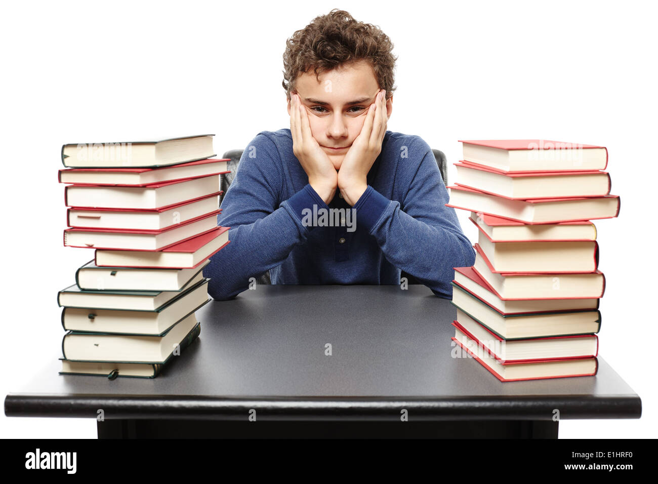 Studio shot of hopeless student with face in hands sitting at his desk ...