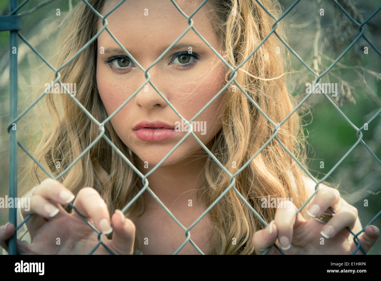 Portrait of young woman behind wire fence Stock Photo - Alamy
