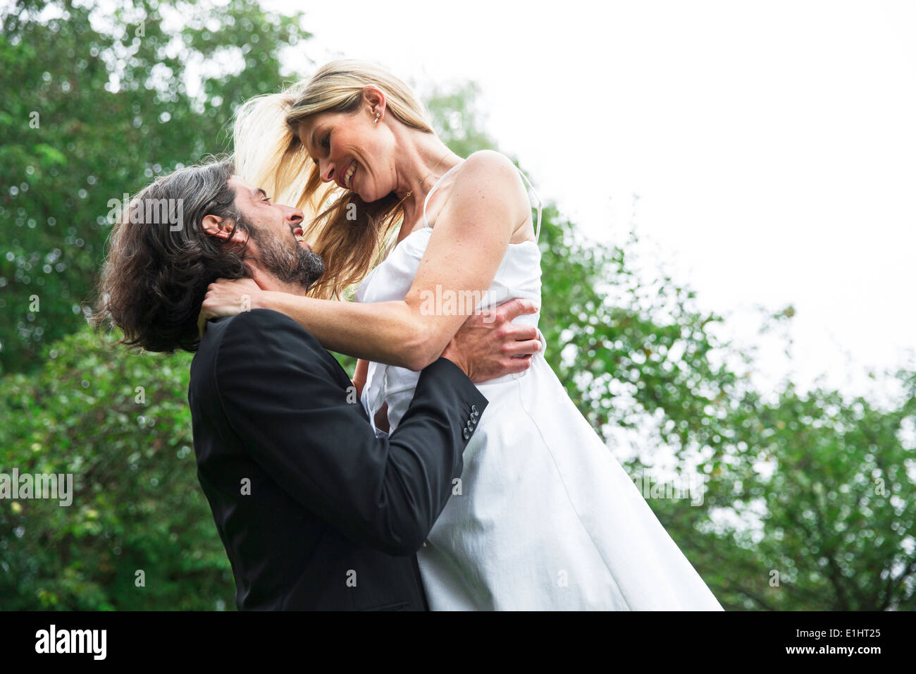 Happy groom lifting up bride in garden Stock Photo - Alamy