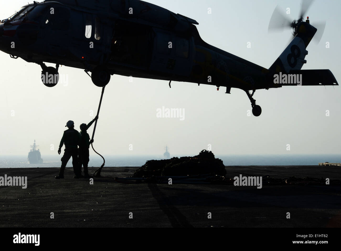U.S. Sailors hook cargo nets to an MH-60S Knighthawk helicopter ...
