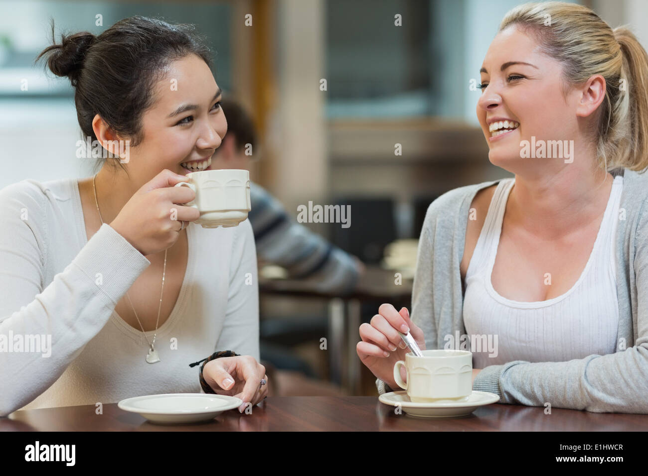 Two laughing students in college coffee shop Stock Photo - Alamy