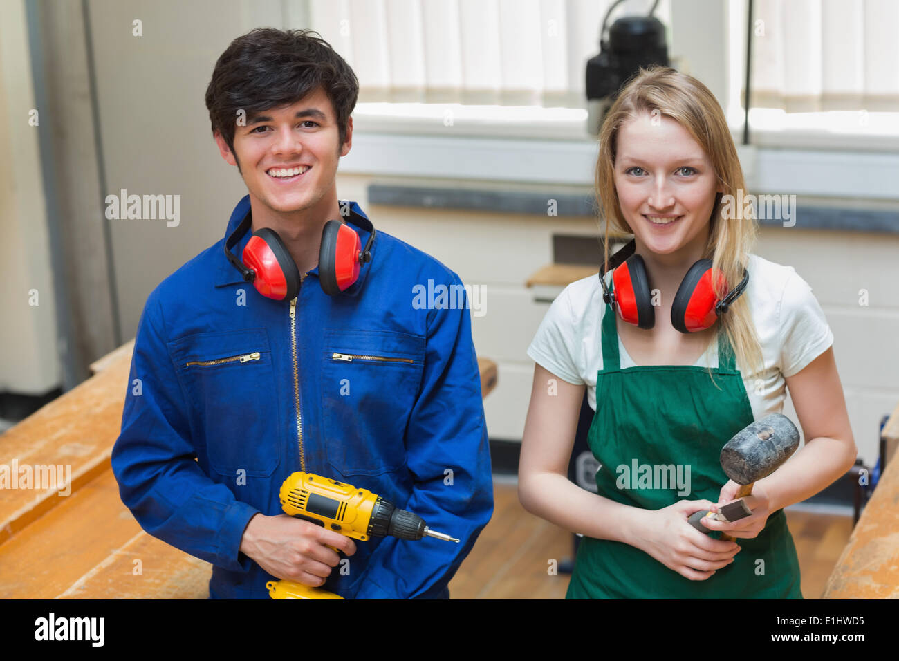 Two students holding a driller and a hammer Stock Photo - Alamy