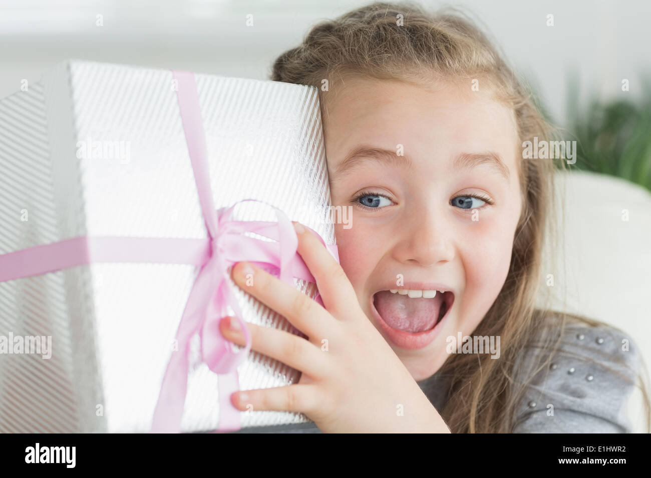 Surprised girl shaking a present Stock Photo - Alamy