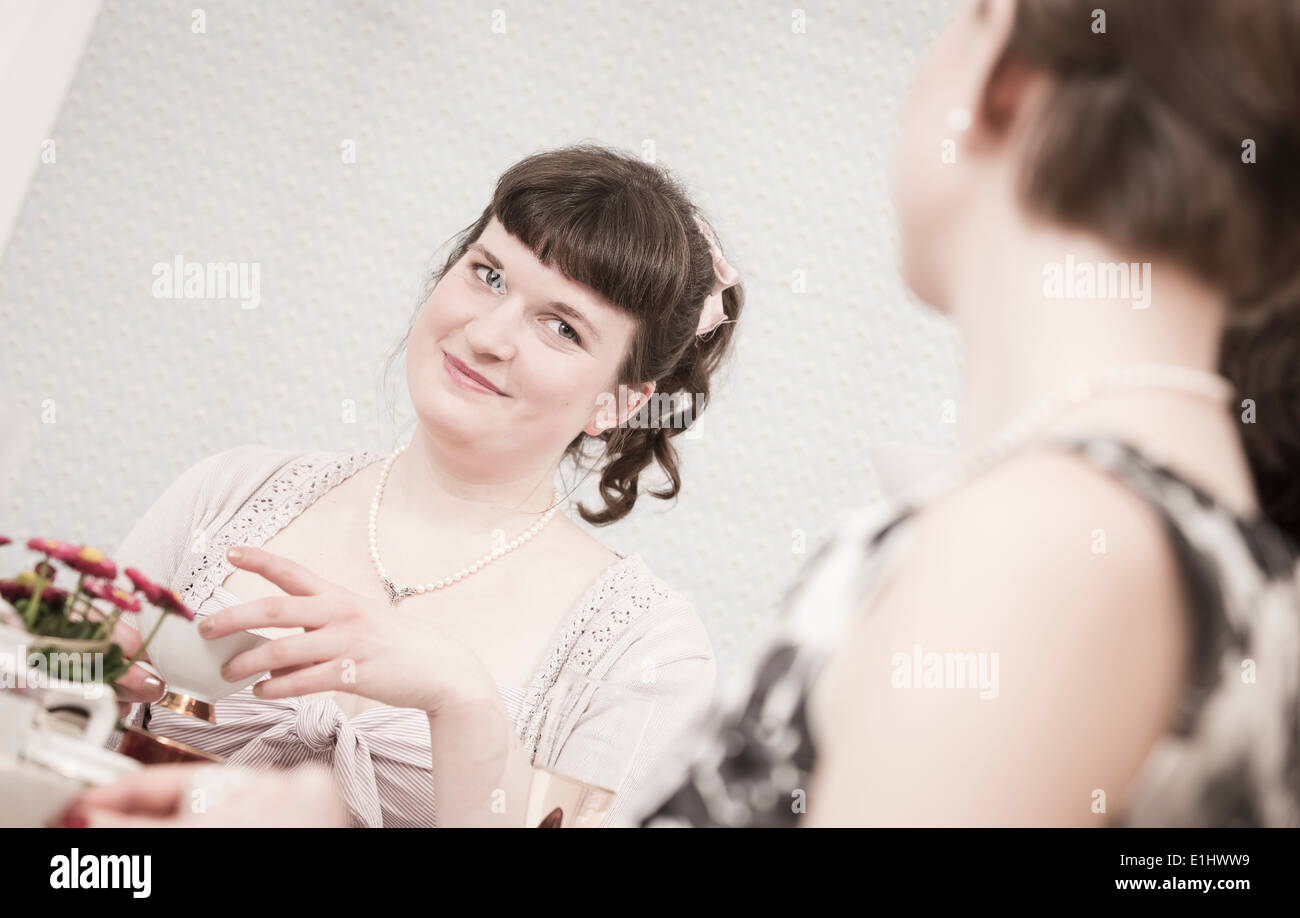 Two young women on a retro style tea party Stock Photo - Alamy