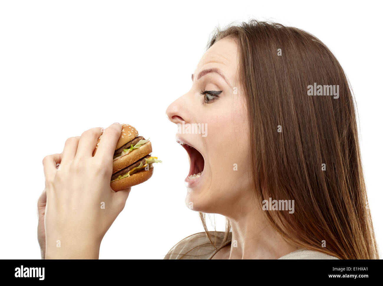 Young caucasian woman preparing to bite a big burger, isolated on white ...