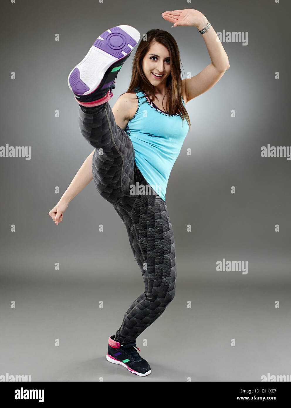 Young woman kicking high in a funny pose over gray background Stock ...