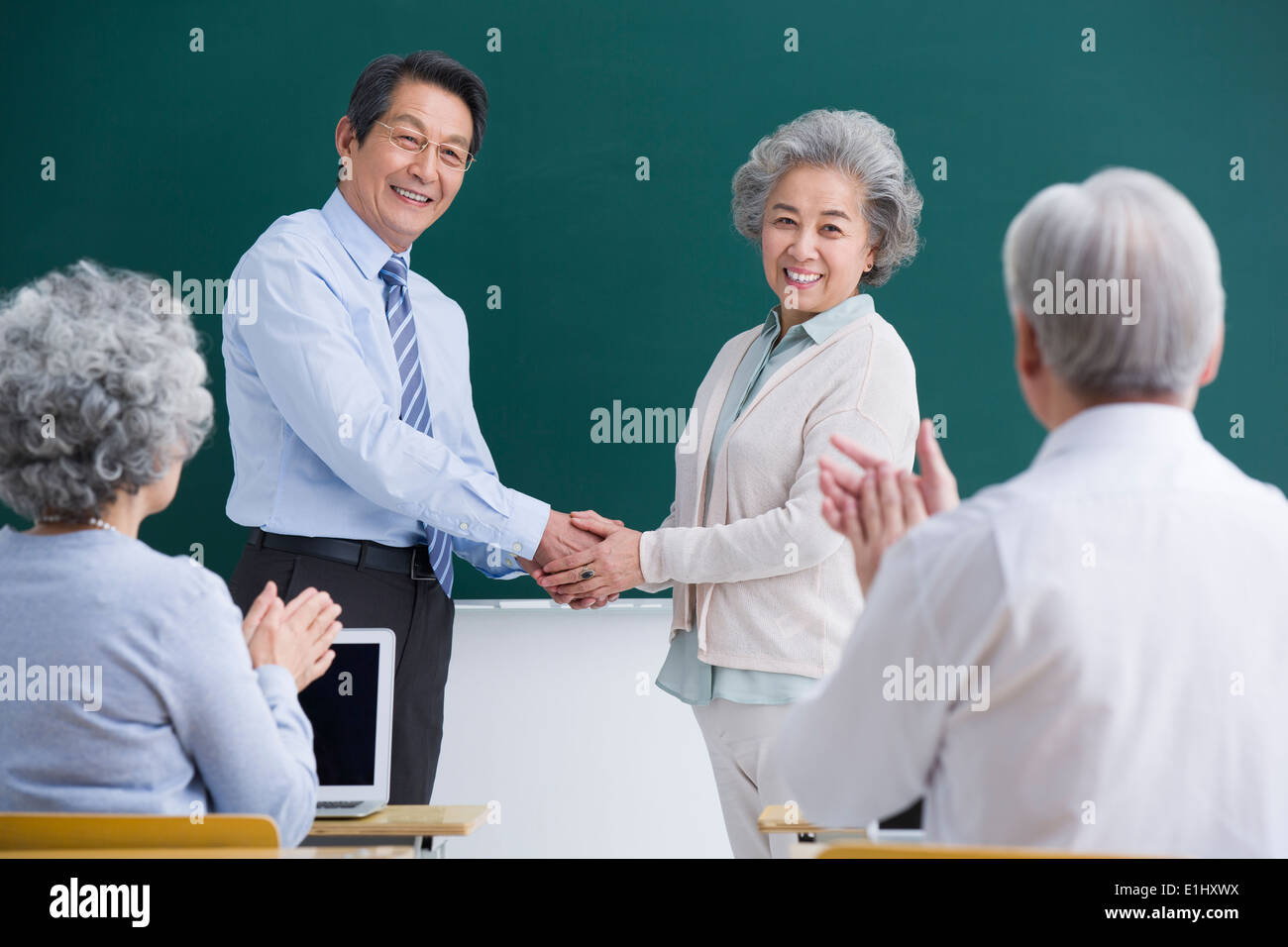 Senior student having a handshake with teacher in classroom Stock Photo ...