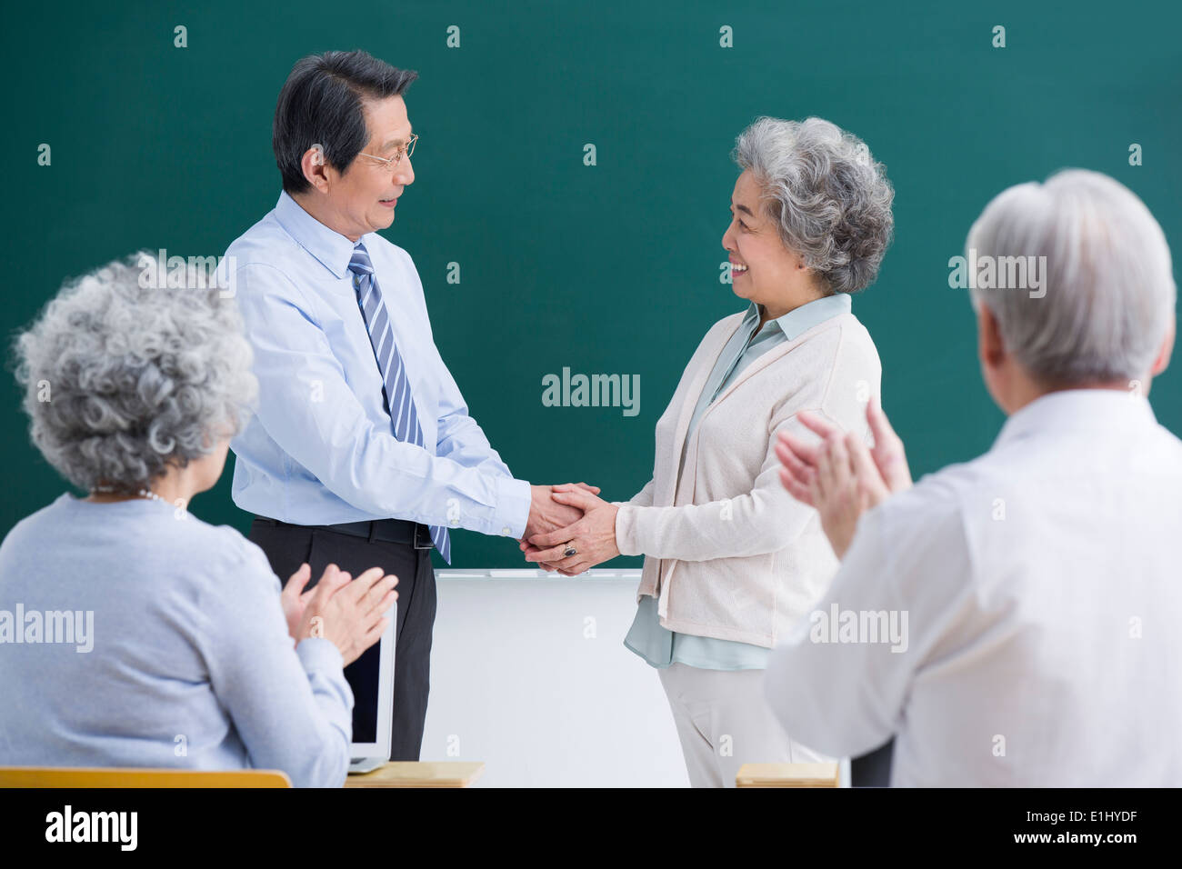 Senior student having a handshake with teacher in classroom Stock Photo ...