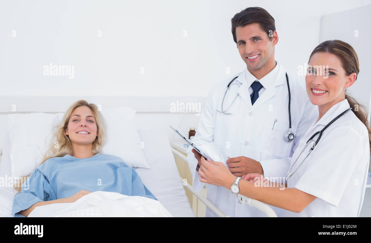 Smiling doctors standing next to a patient Stock Photo - Alamy
