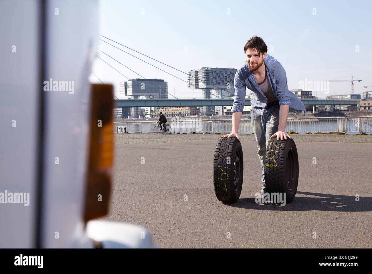 Man rolling car tyres Stock Photo - Alamy