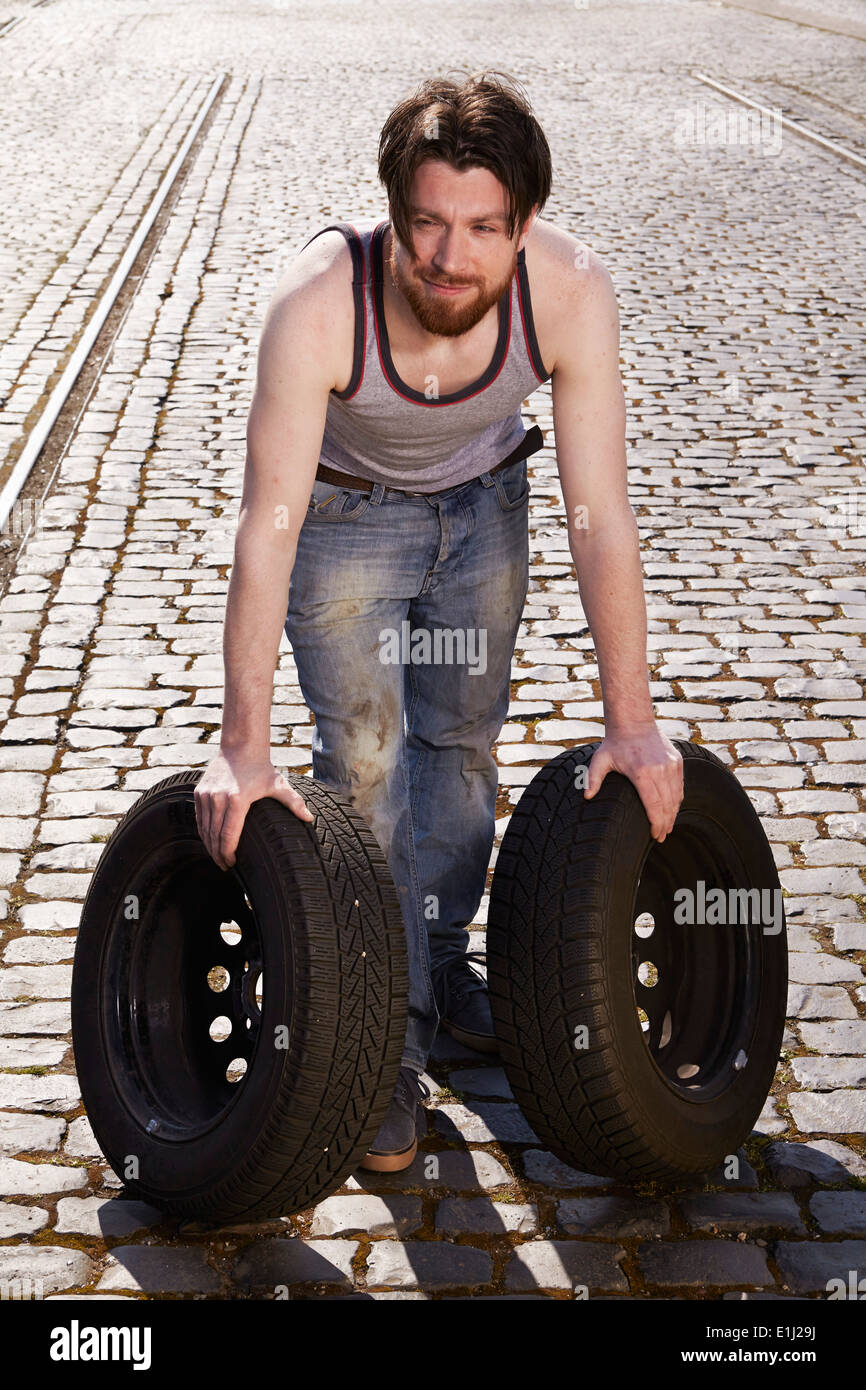 Man rolling car tyres Stock Photo - Alamy