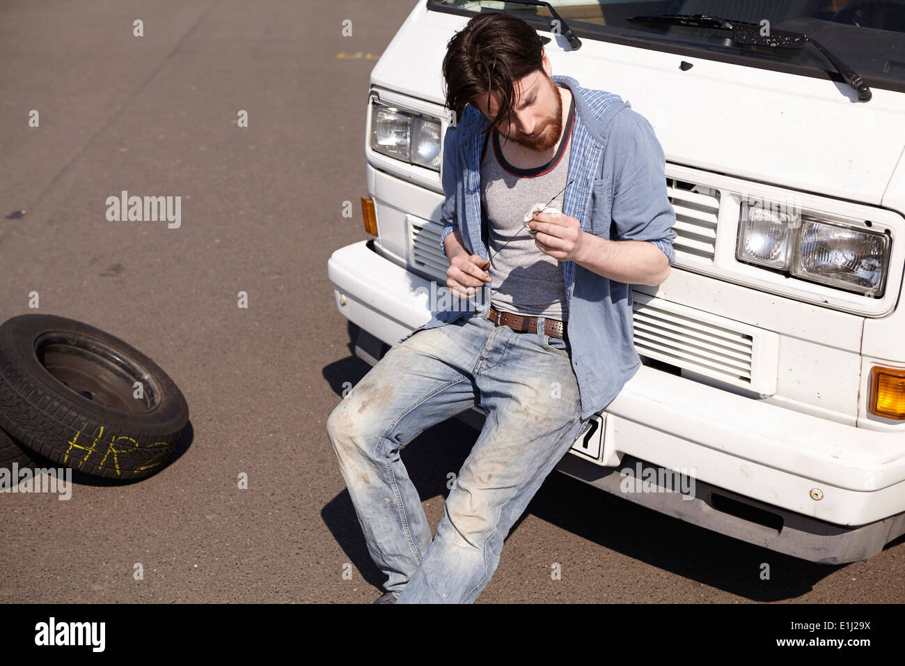 Man leaning against car looking at dipstick Stock Photo - Alamy