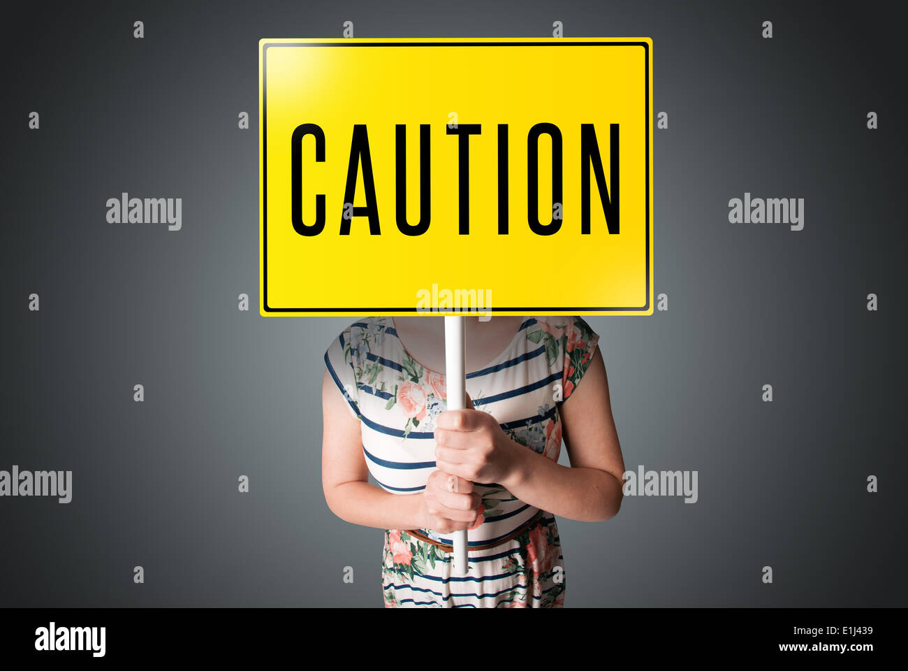 Young woman holding a caution sign Stock Photo - Alamy